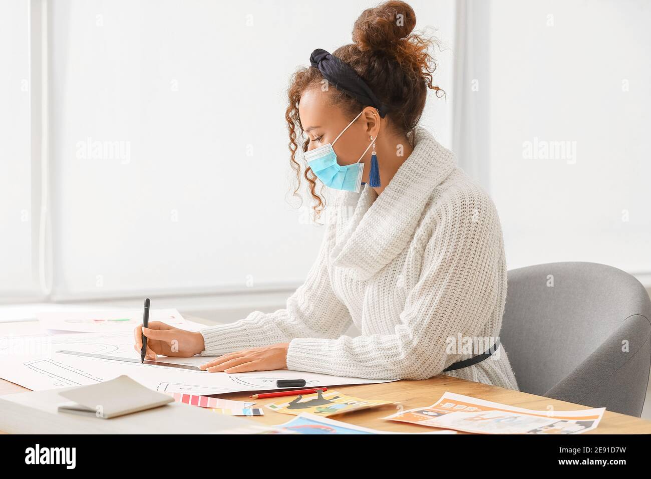 Female fashion designer wearing medical mask in studio Stock Photo - Alamy