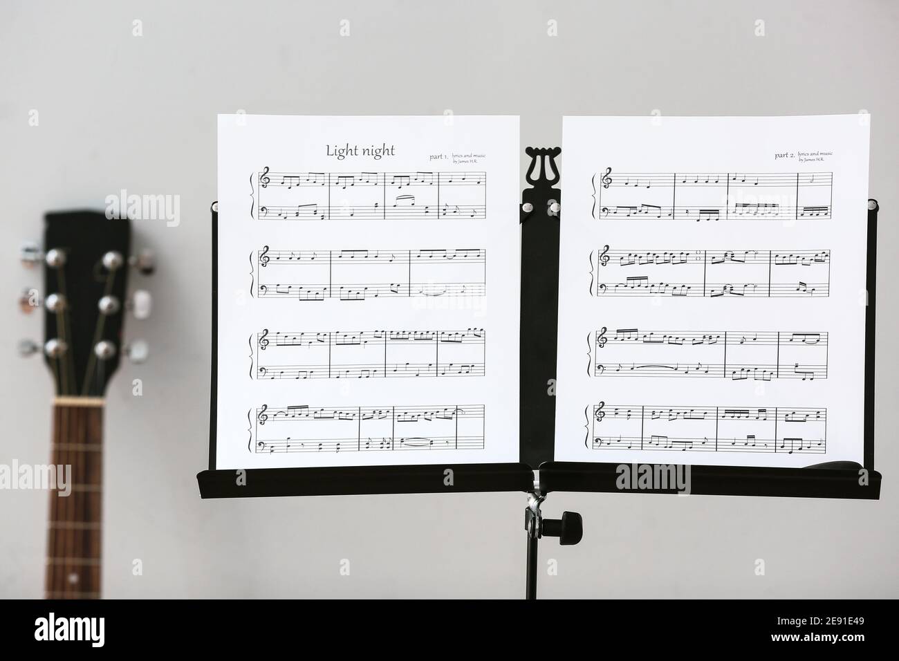 Note stand with music sheets and guitar on light background Stock Photo ...