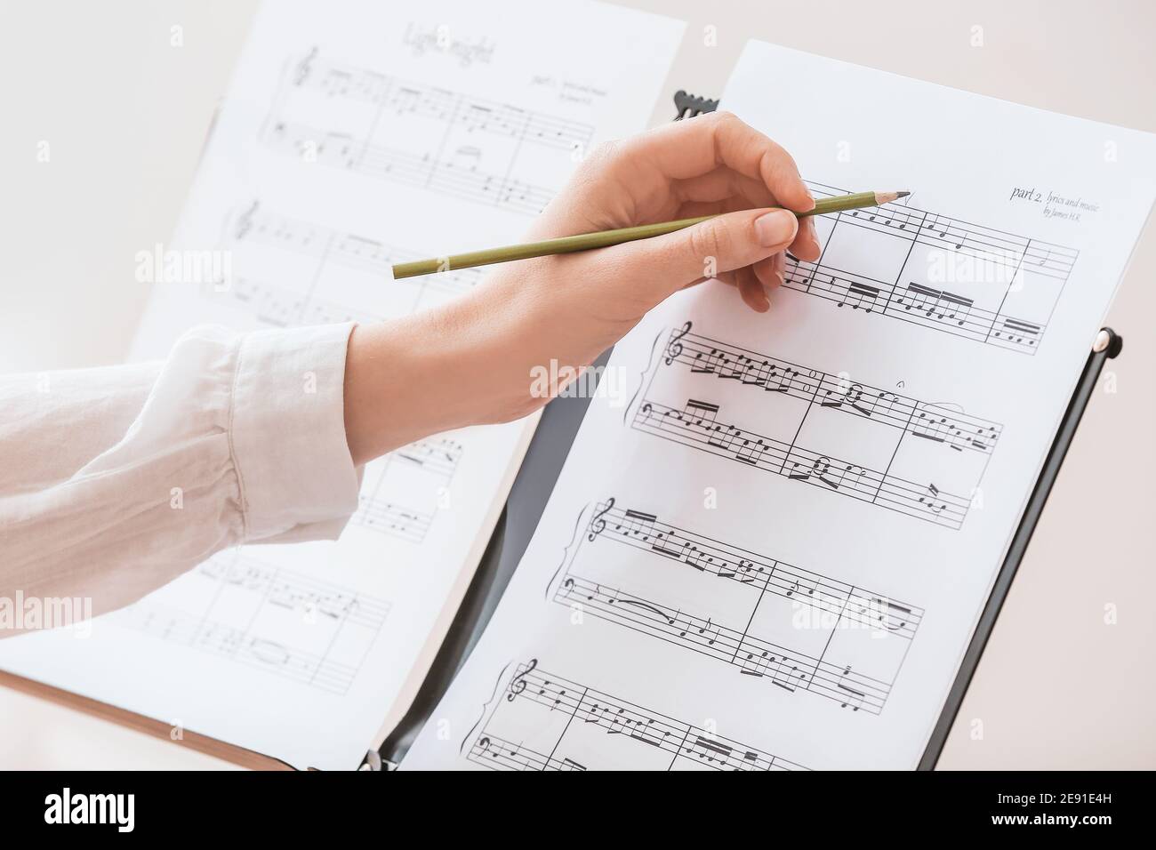 Female hand and note stand with music sheets on light background Stock ...