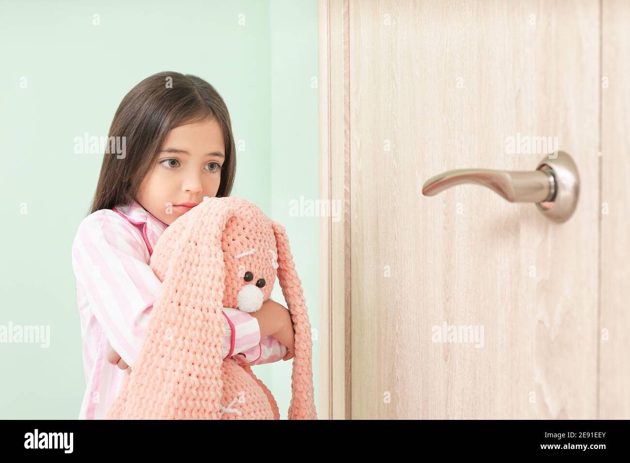 Scared little girl standing near closed door Stock Photo - Alamy