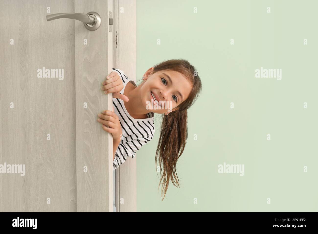 Cute little girl looking out the door Stock Photo - Alamy