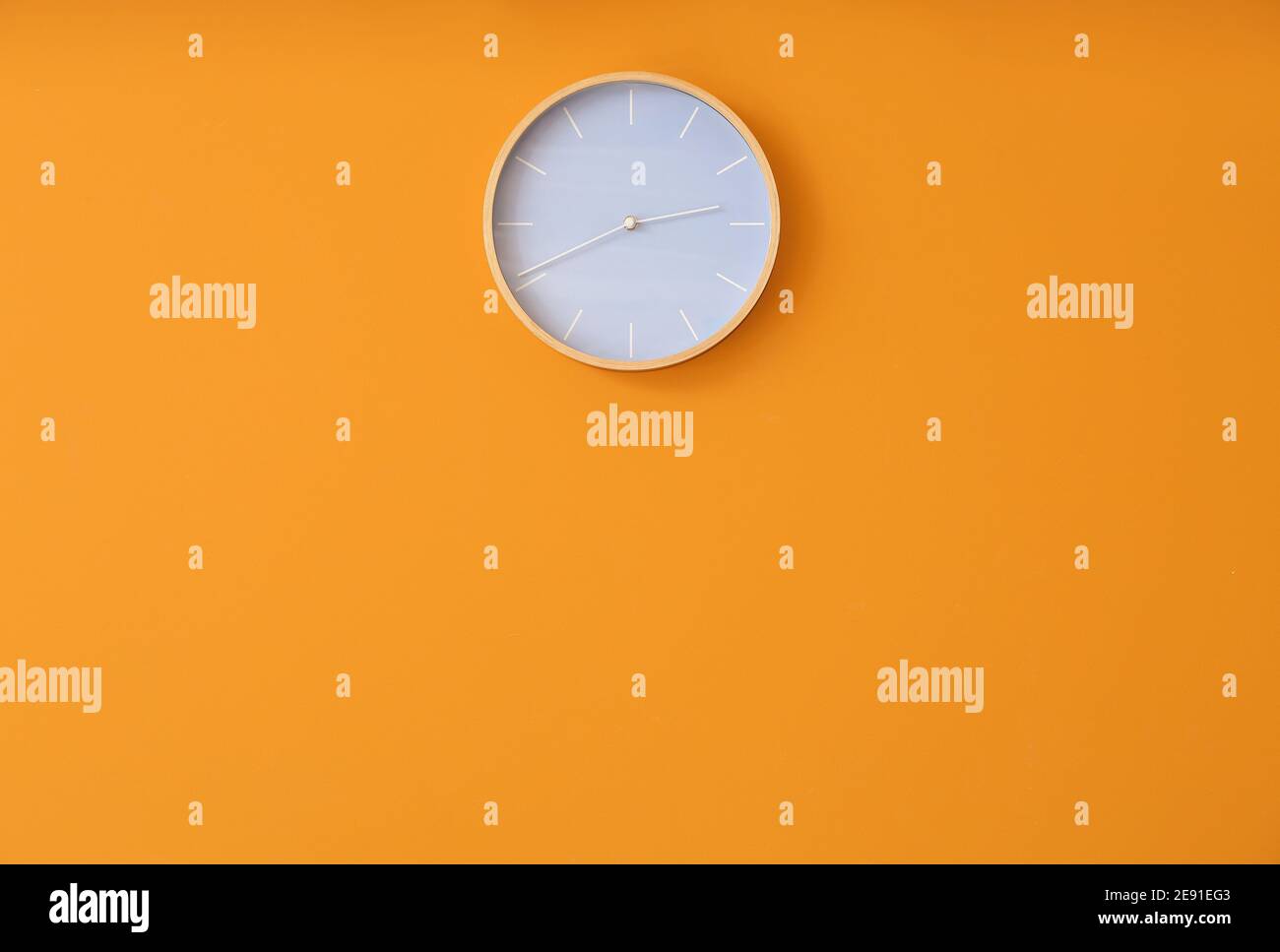 Modern clock hanging on color wall Stock Photo - Alamy