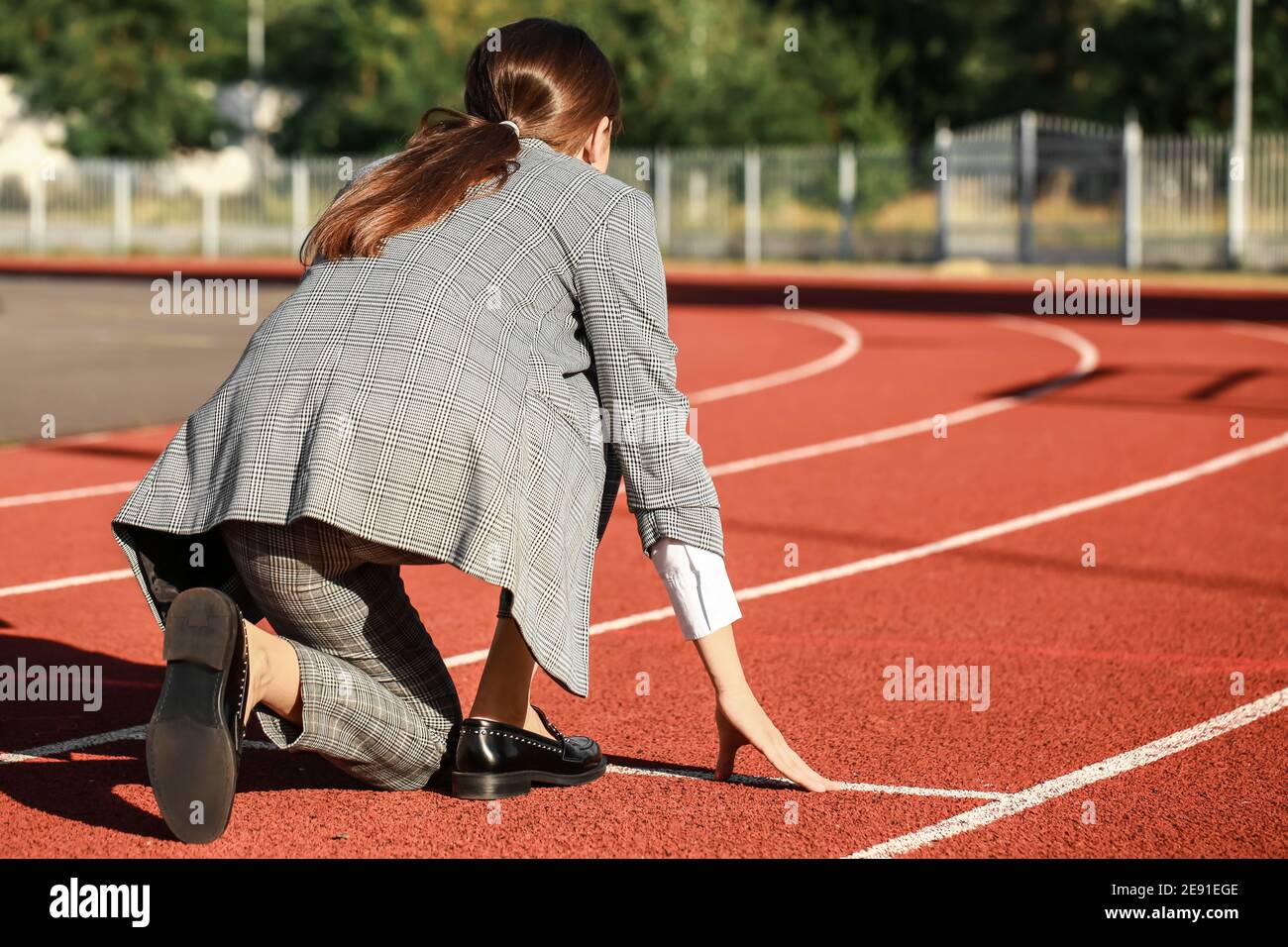 Young businesswoman standing in crouch start position at stadium Stock ...