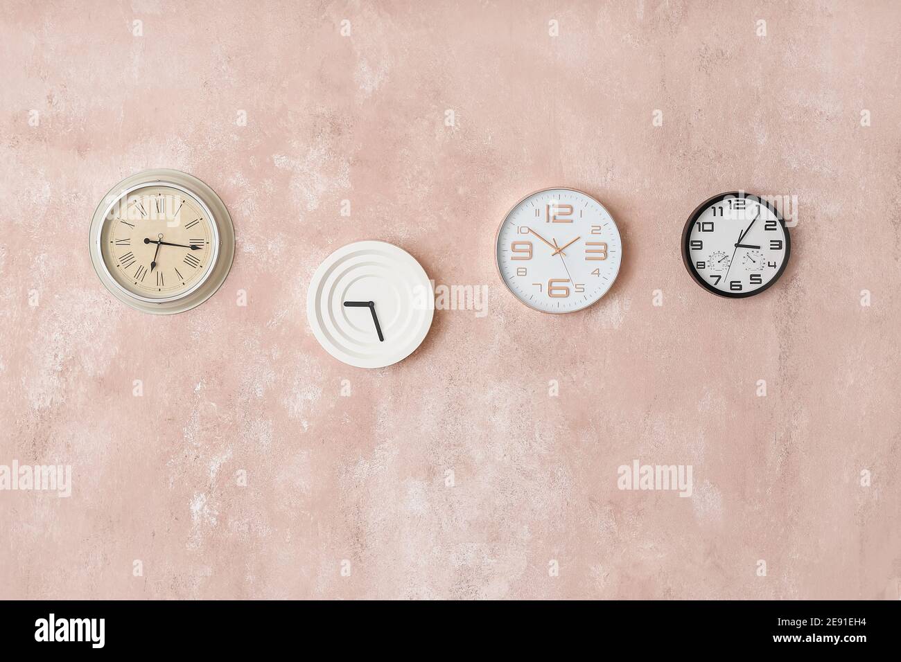 Different clocks hanging on color wall Stock Photo - Alamy