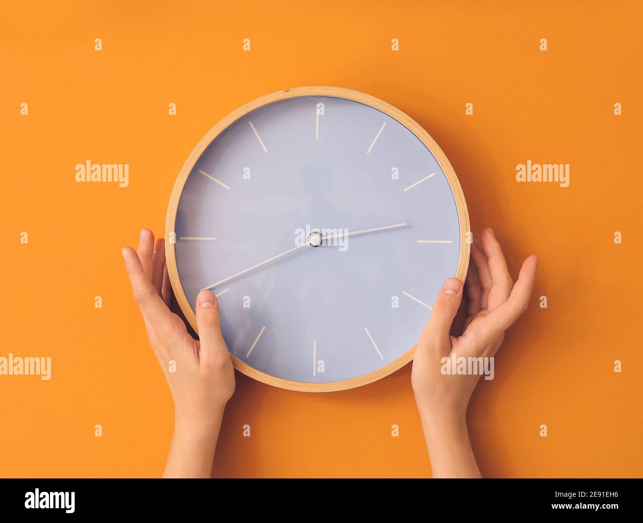 Woman hanging hands of clock hi-res stock photography and images - Alamy