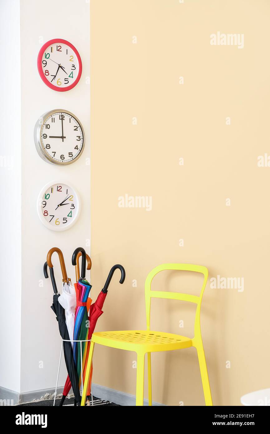 Different clocks hanging on color wall in room Stock Photo - Alamy
