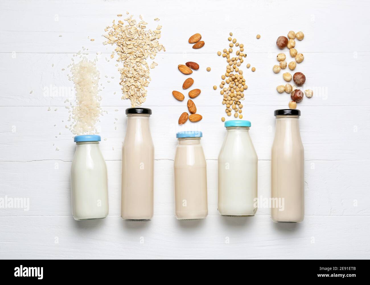 Bottles of different vegan milk on light background Stock Photo - Alamy