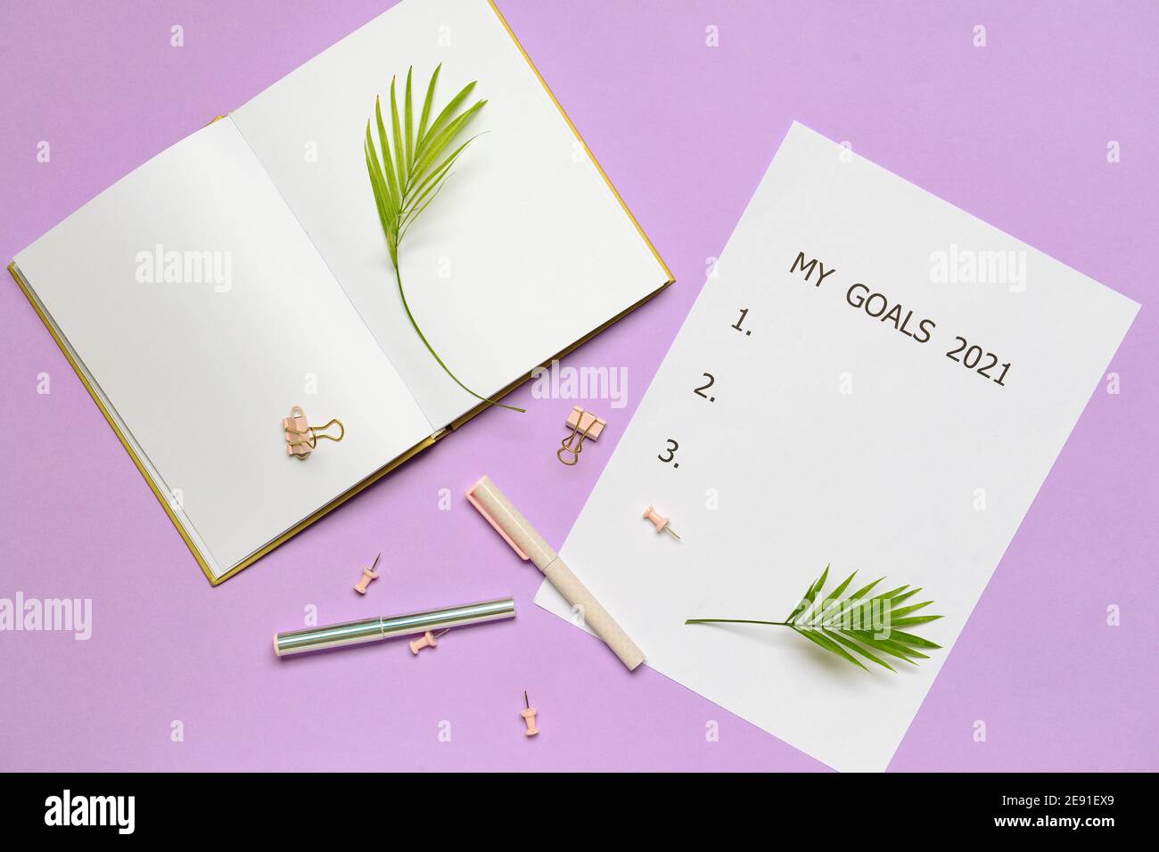 Paper sheet with text MY GOALS 2021 and stationery on color background ...