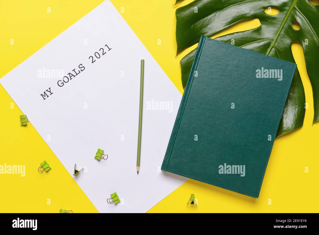 Paper sheet with text MY GOALS 2021 and stationery on color background ...