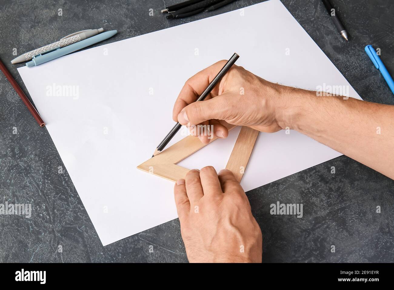 Male hands with blank paper sheet, pen and ruler on dark background ...