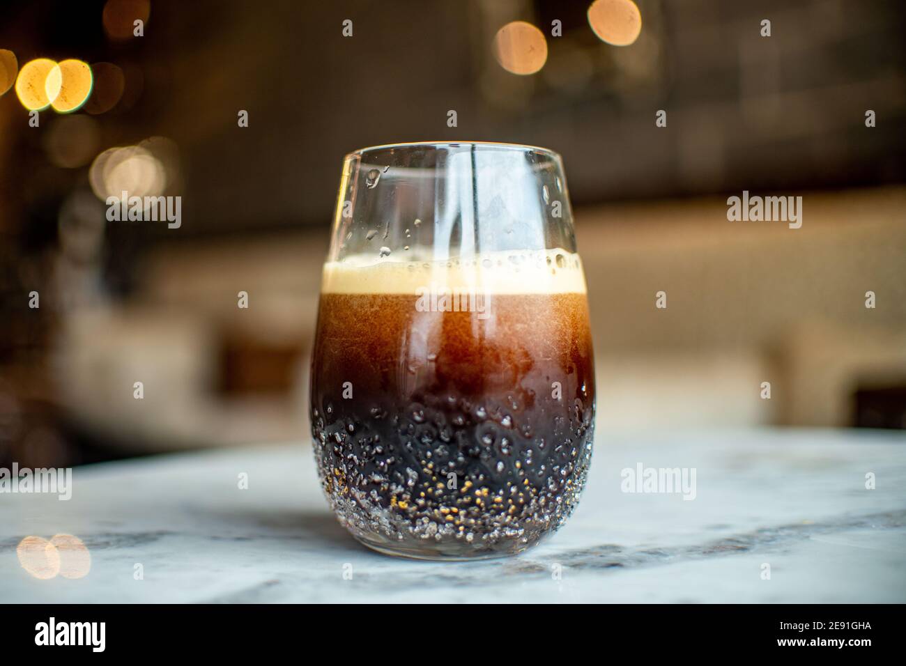 Iced cold brew coffee with a coffee shop background Stock Photo - Alamy