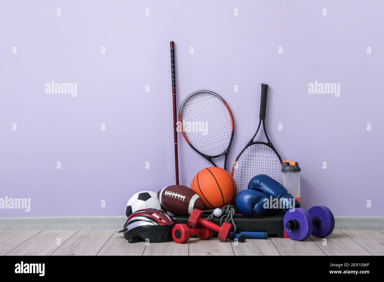 Set of sports equipment on floor near color wall Stock Photo - Alamy