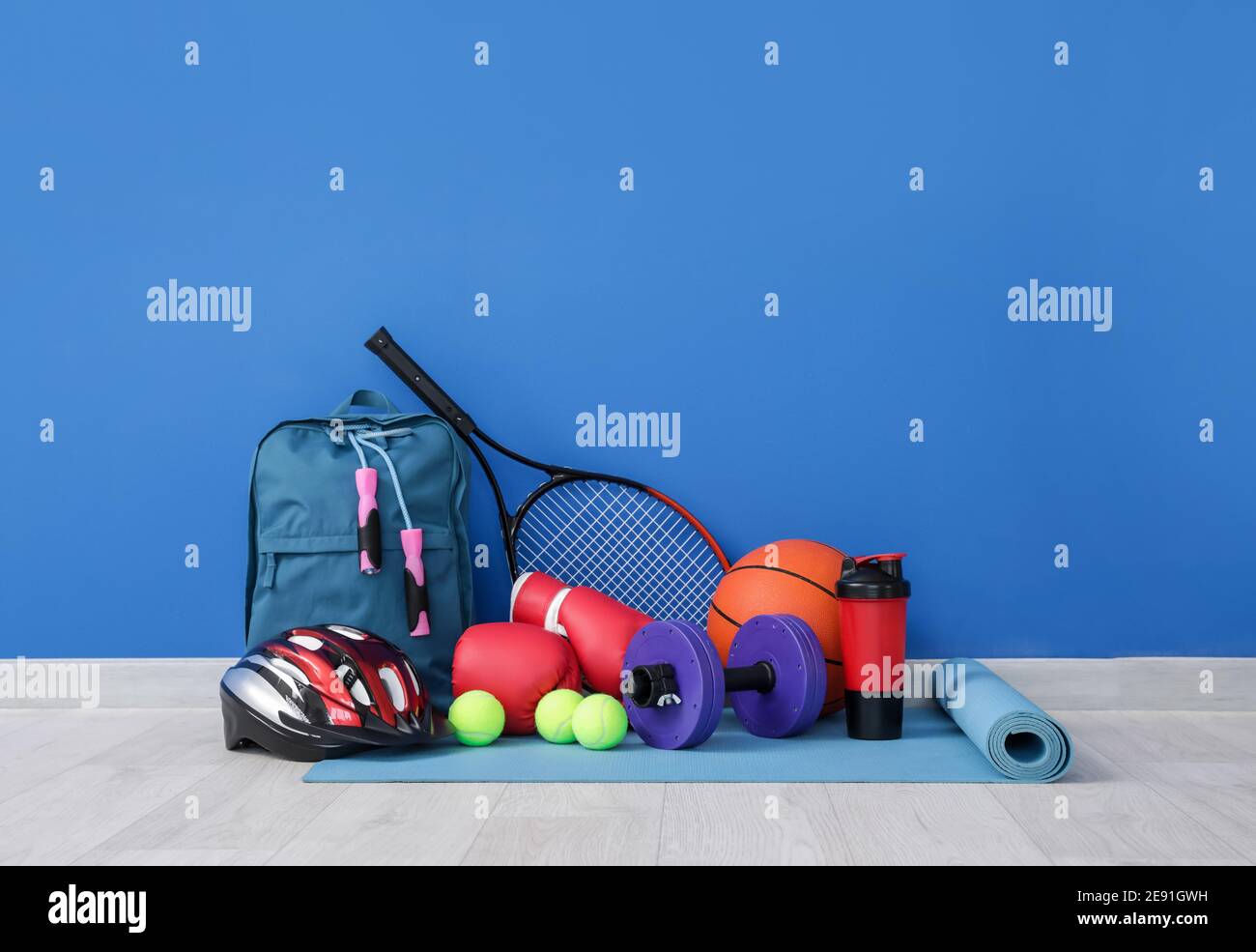Set of sports equipment on floor near color wall Stock Photo - Alamy