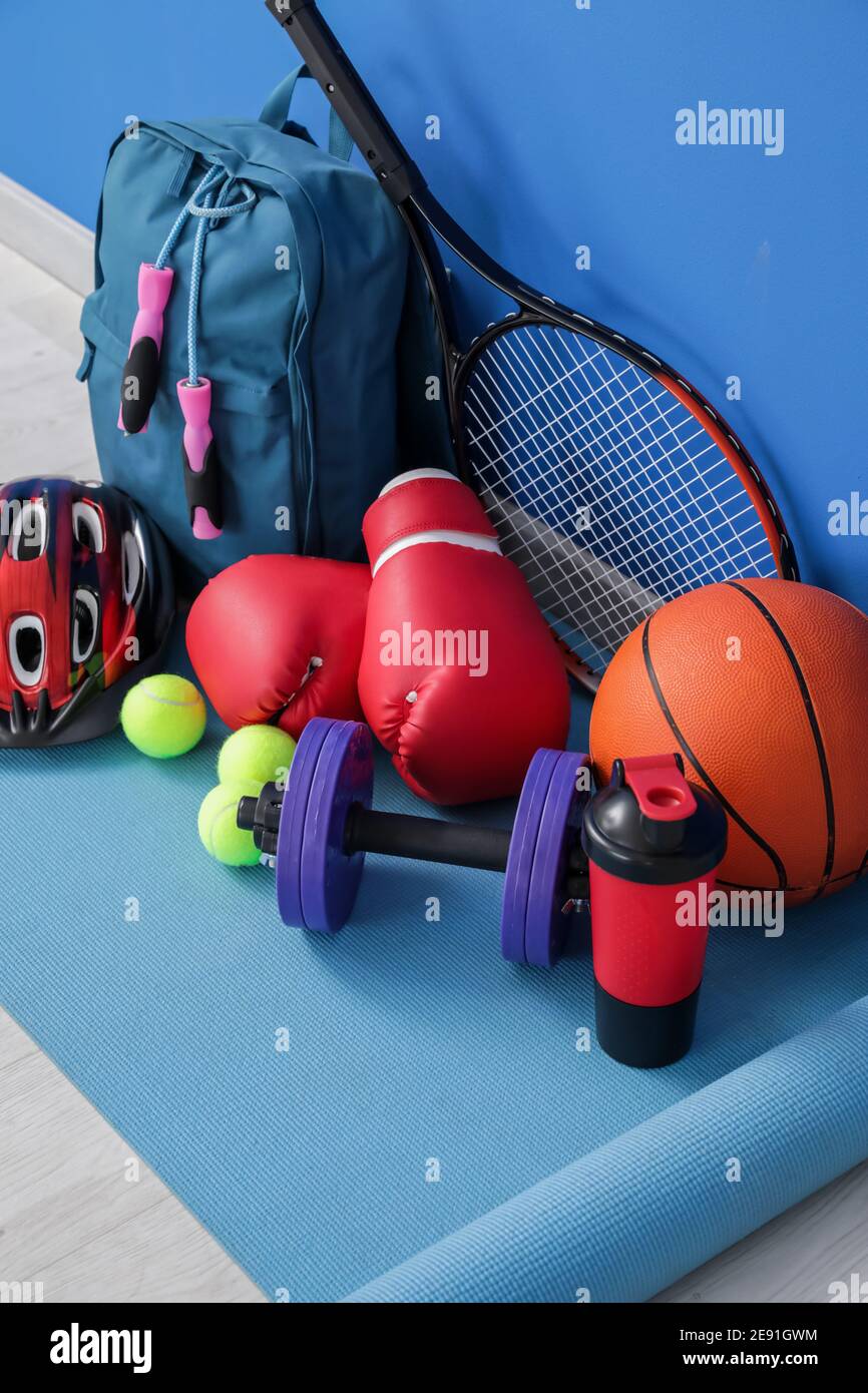 Set of sports equipment on floor near color wall Stock Photo - Alamy