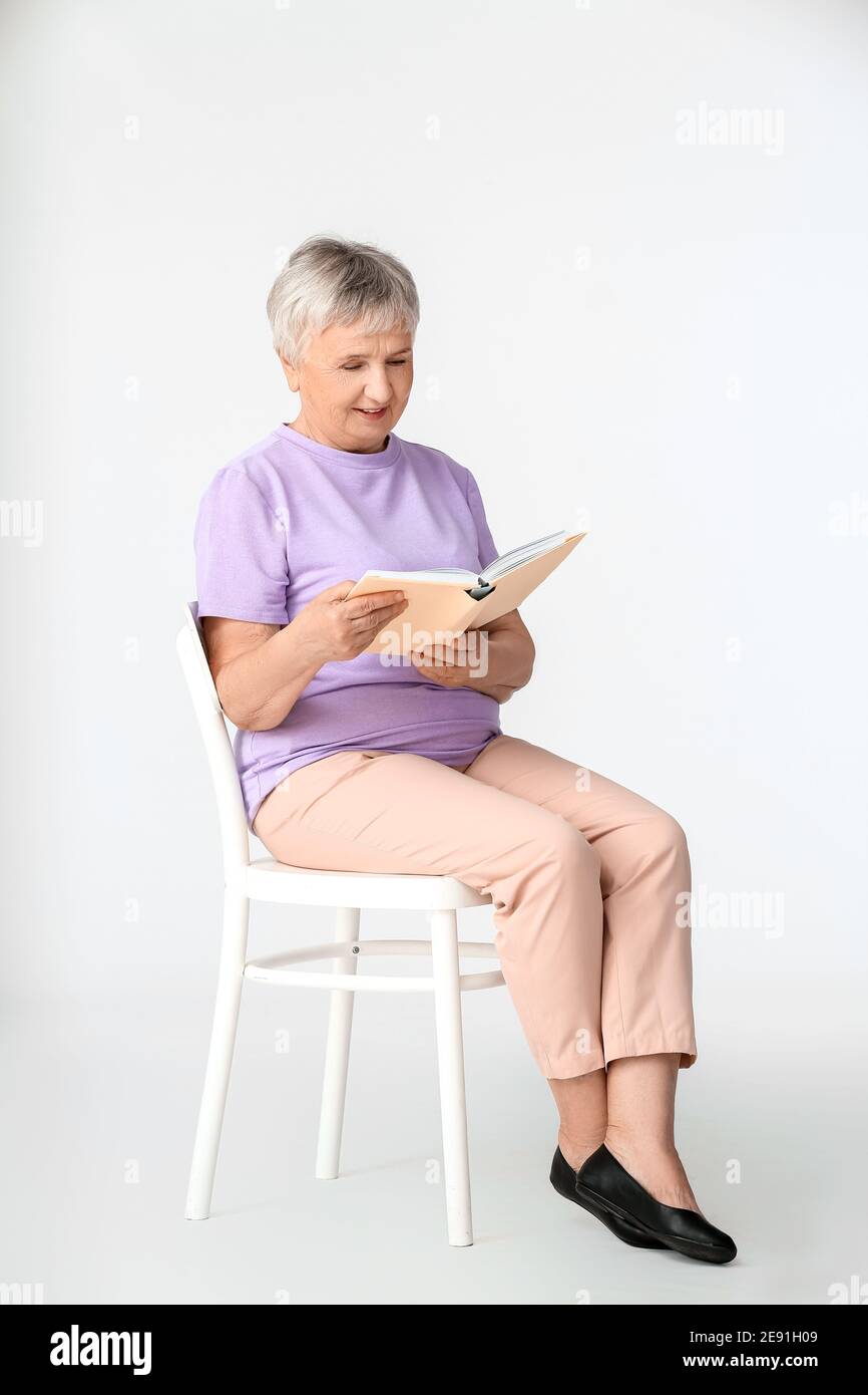 Senior woman reading book on white background Stock Photo - Alamy
