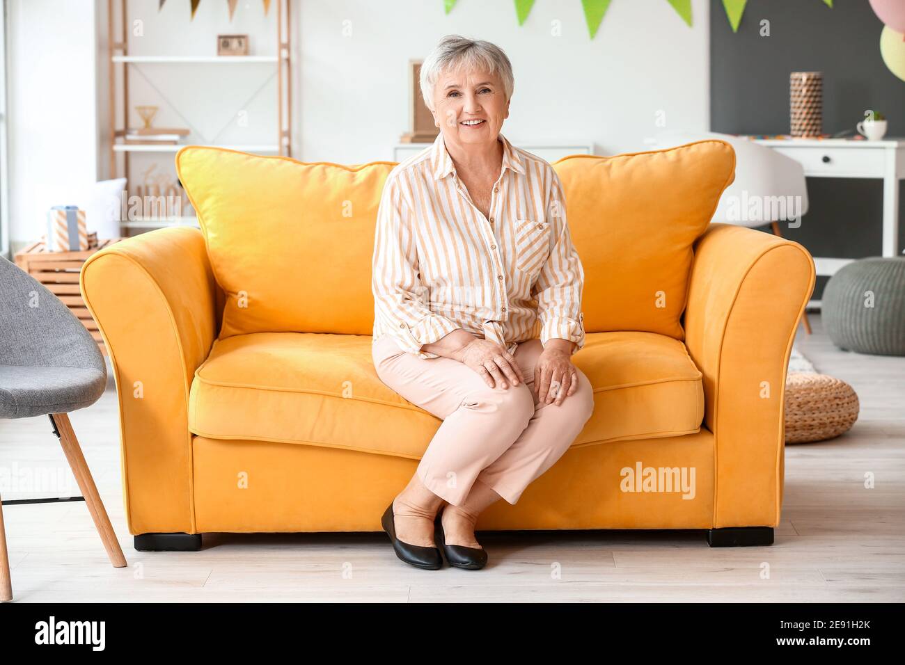 Senior woman sitting on sofa at home Stock Photo - Alamy