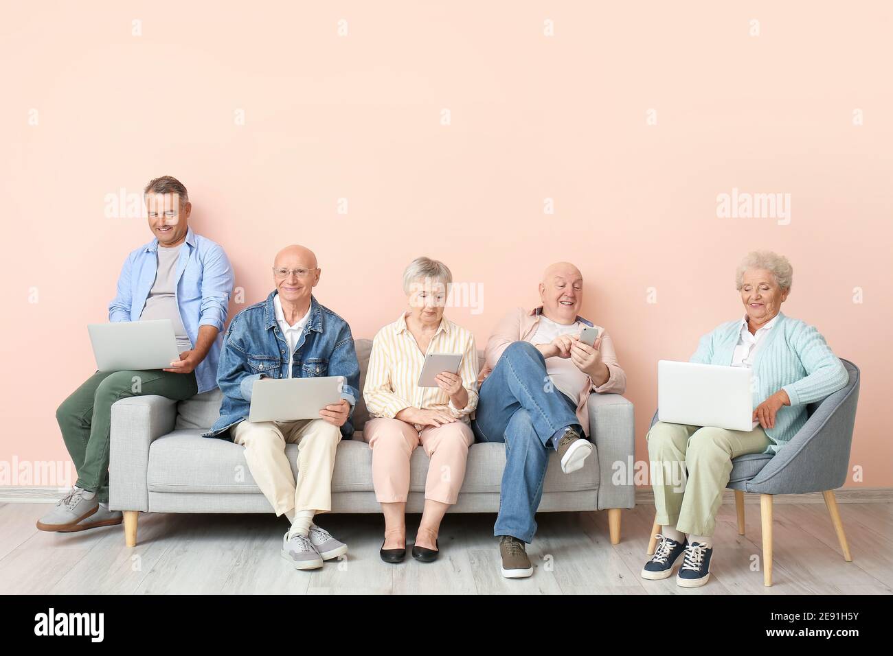 Senior people with different devices sitting on sofa in room Stock ...