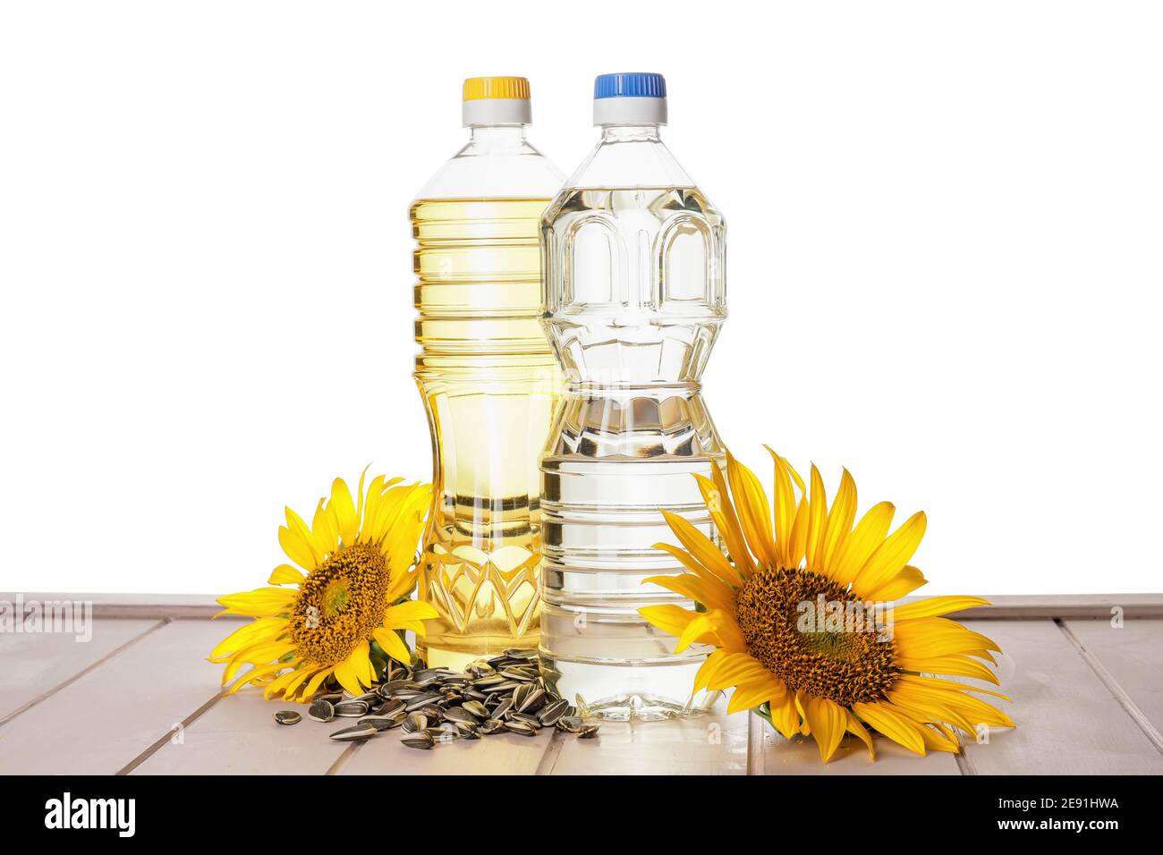 Bottles of oil, seeds and sunflowers on table against white background ...