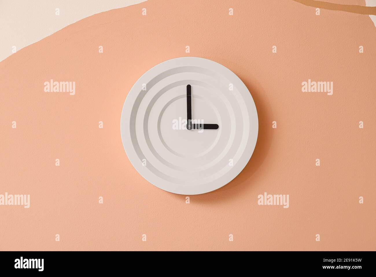 Modern clock hanging on color wall Stock Photo - Alamy