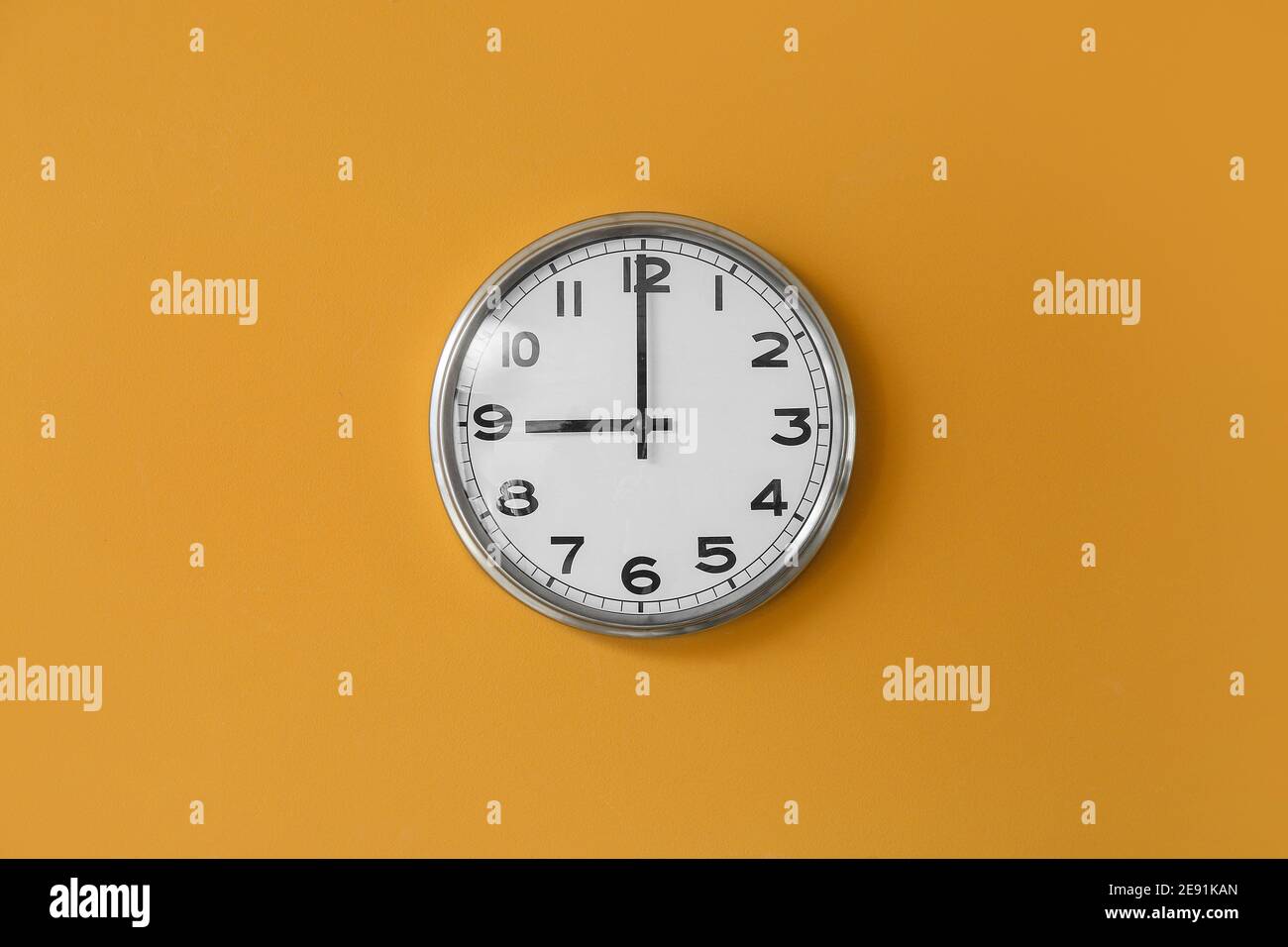 Modern clock hanging on color wall Stock Photo - Alamy