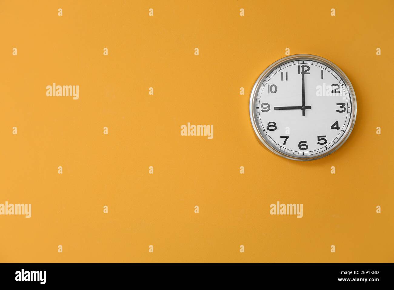 Modern clock hanging on color wall Stock Photo - Alamy