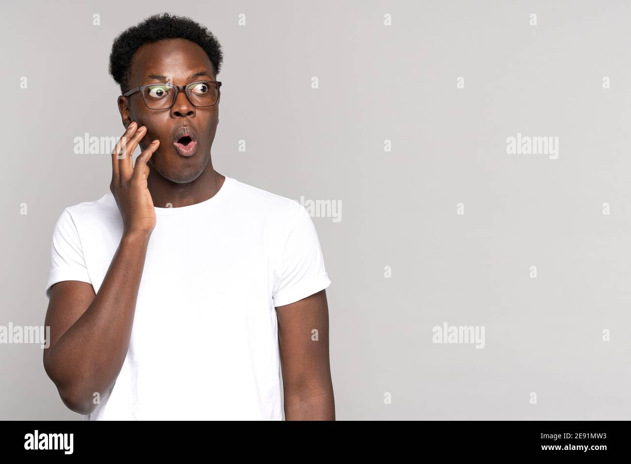 Surprised afro man makes big eyes opens, touching her face, shocked ...