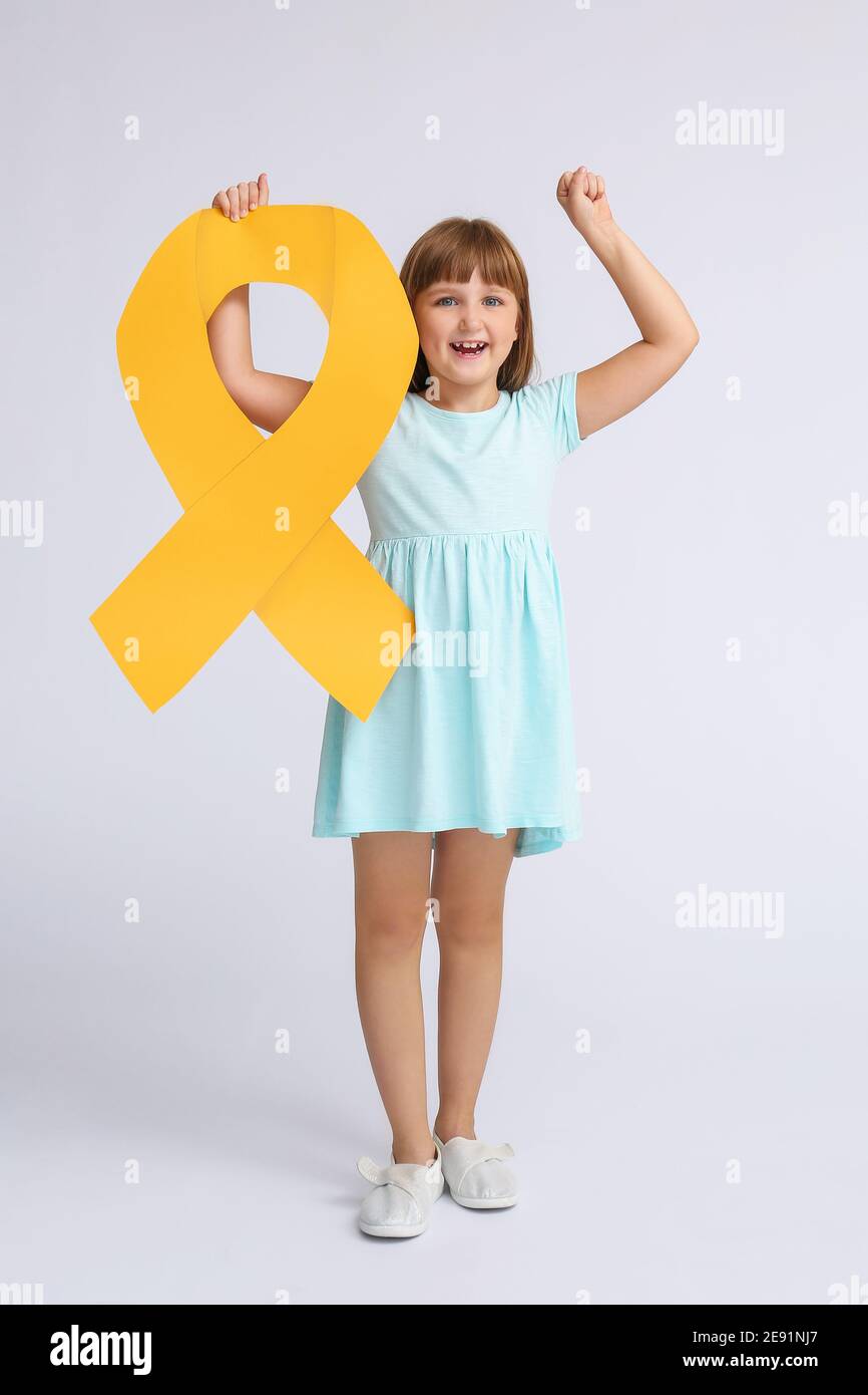 Little girl with golden ribbon on grey background. Childhood cancer ...