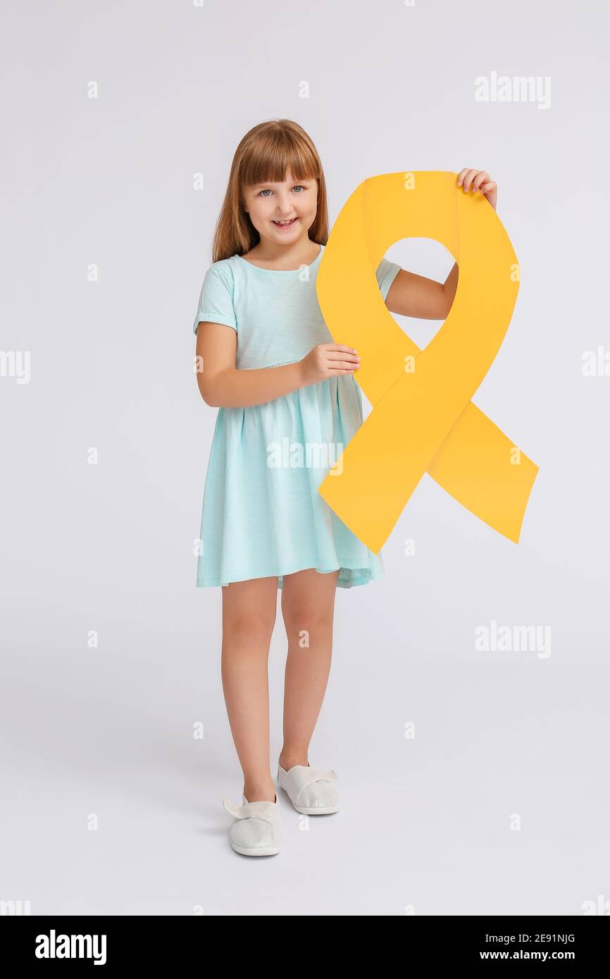 Little girl with golden ribbon on grey background. Childhood cancer ...