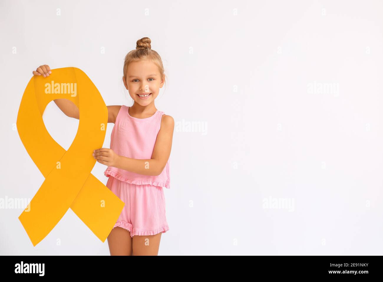 Little girl with golden ribbon on light background. Childhood cancer ...