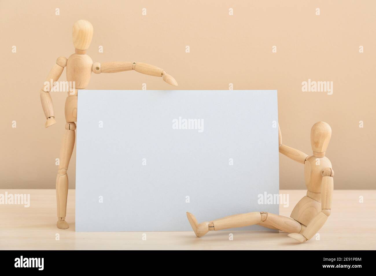 Wooden mannequins with empty paper sheet on color background Stock ...