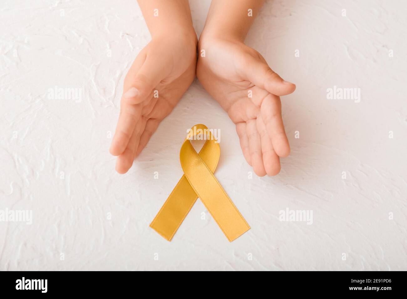 Hands with golden ribbon on white background. Childhood cancer ...