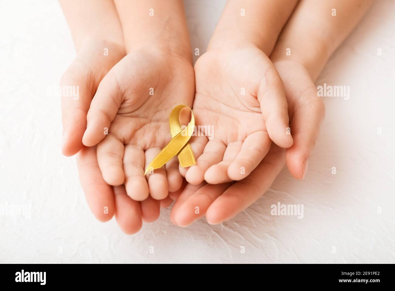 Hands with golden ribbon on white background. Childhood cancer ...