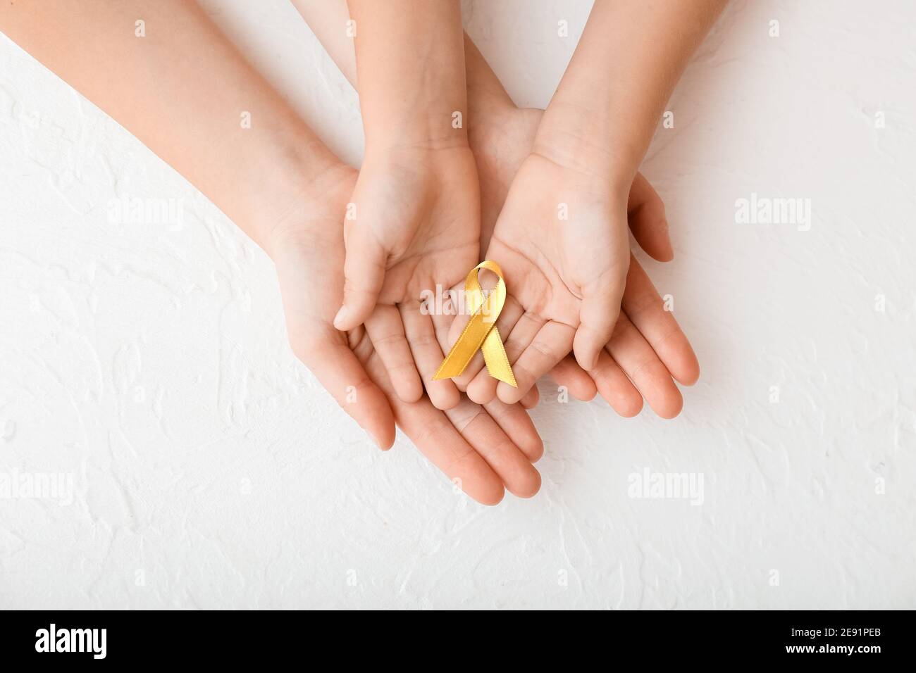 Hands with golden ribbon on white background. Childhood cancer ...