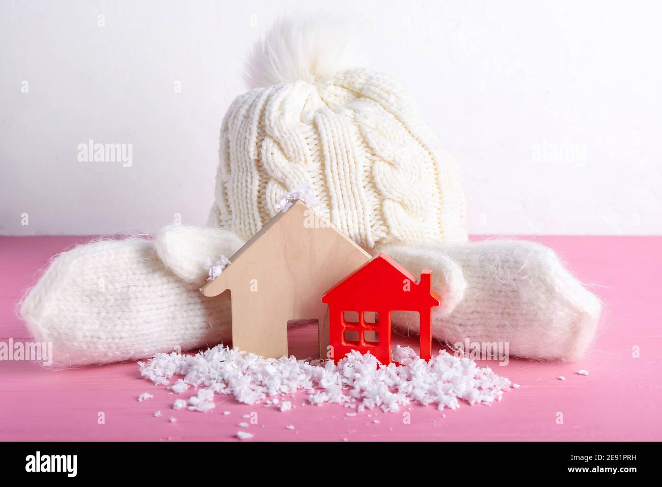 Figures of house, snow and warm clothes on table against white ...