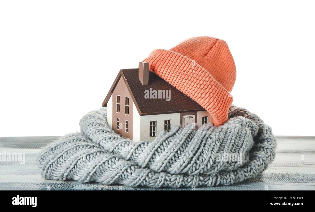 Figure of house and warm clothes on table against white background ...