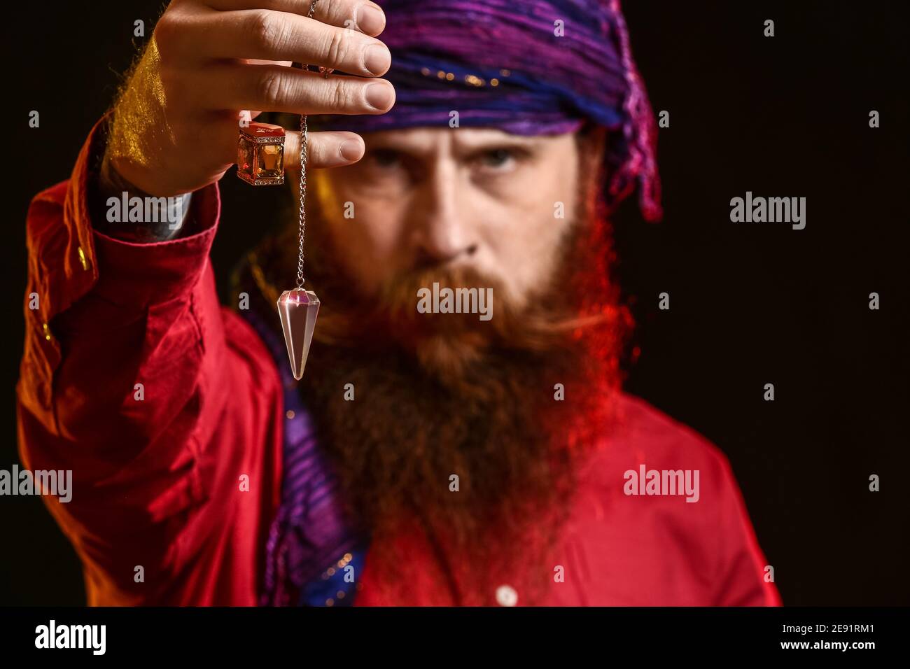 Male fortune teller with pendulum on dark background Stock Photo - Alamy