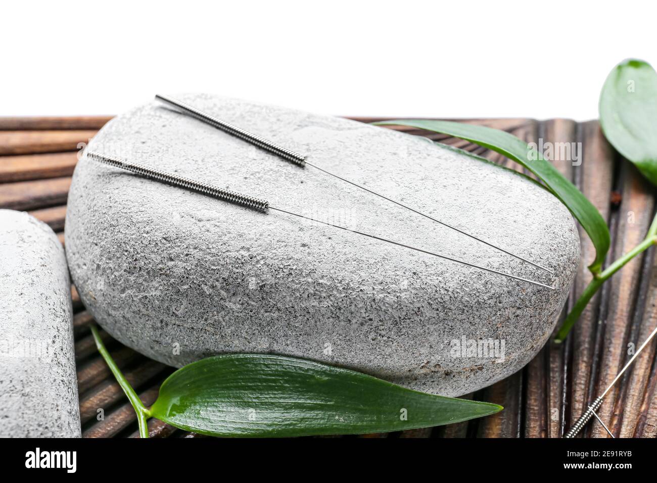 Board with acupuncture needles and spa stone on white background ...