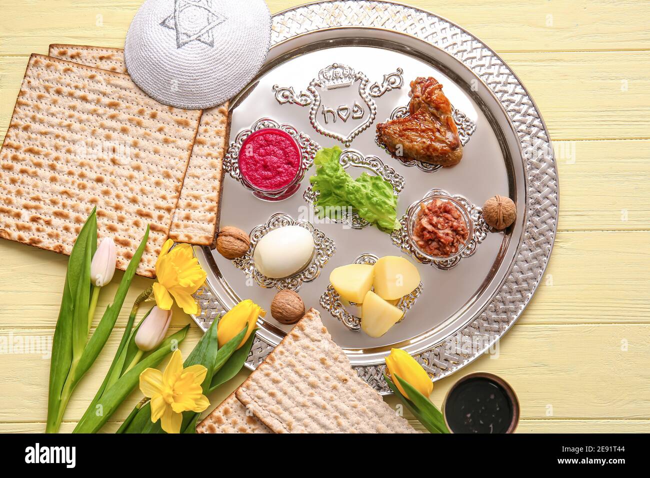 Passover Seder plate with traditional food and Jewish cap on table ...