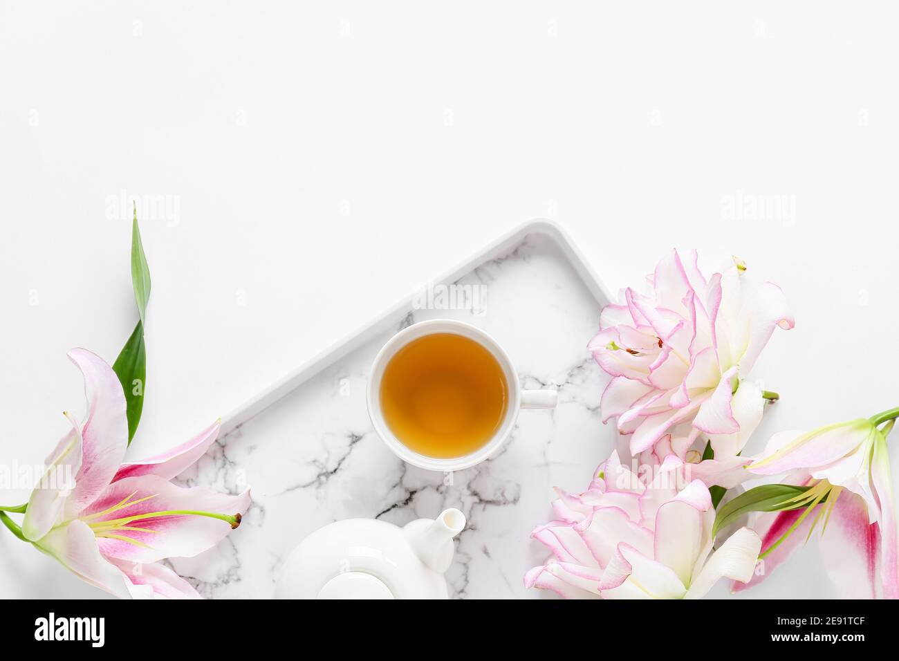 Beautiful lilies and tea on white background Stock Photo - Alamy