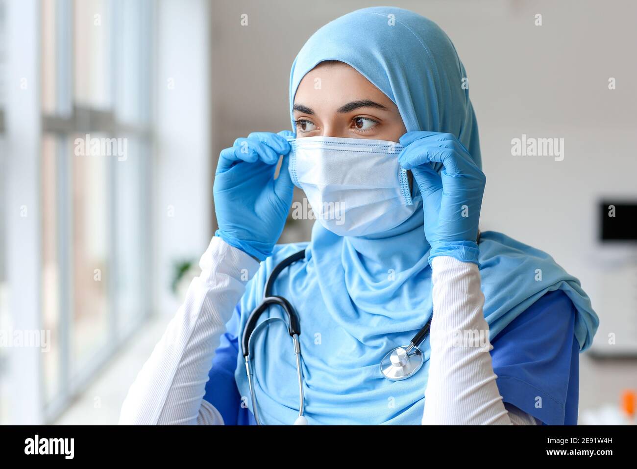 Portrait of female Muslim doctor wearing protective mask in clinic ...