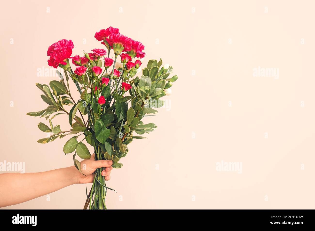 Hand with bouquet of beautiful flowers on color background Stock Photo ...