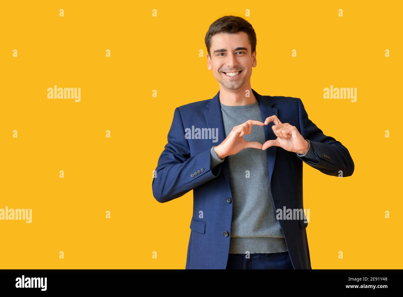 Handsome man making heart with his hands on color background Stock ...