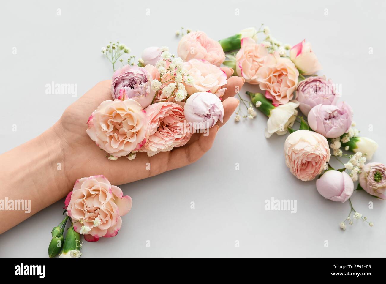 Hand with beautiful flowers on light background Stock Photo - Alamy