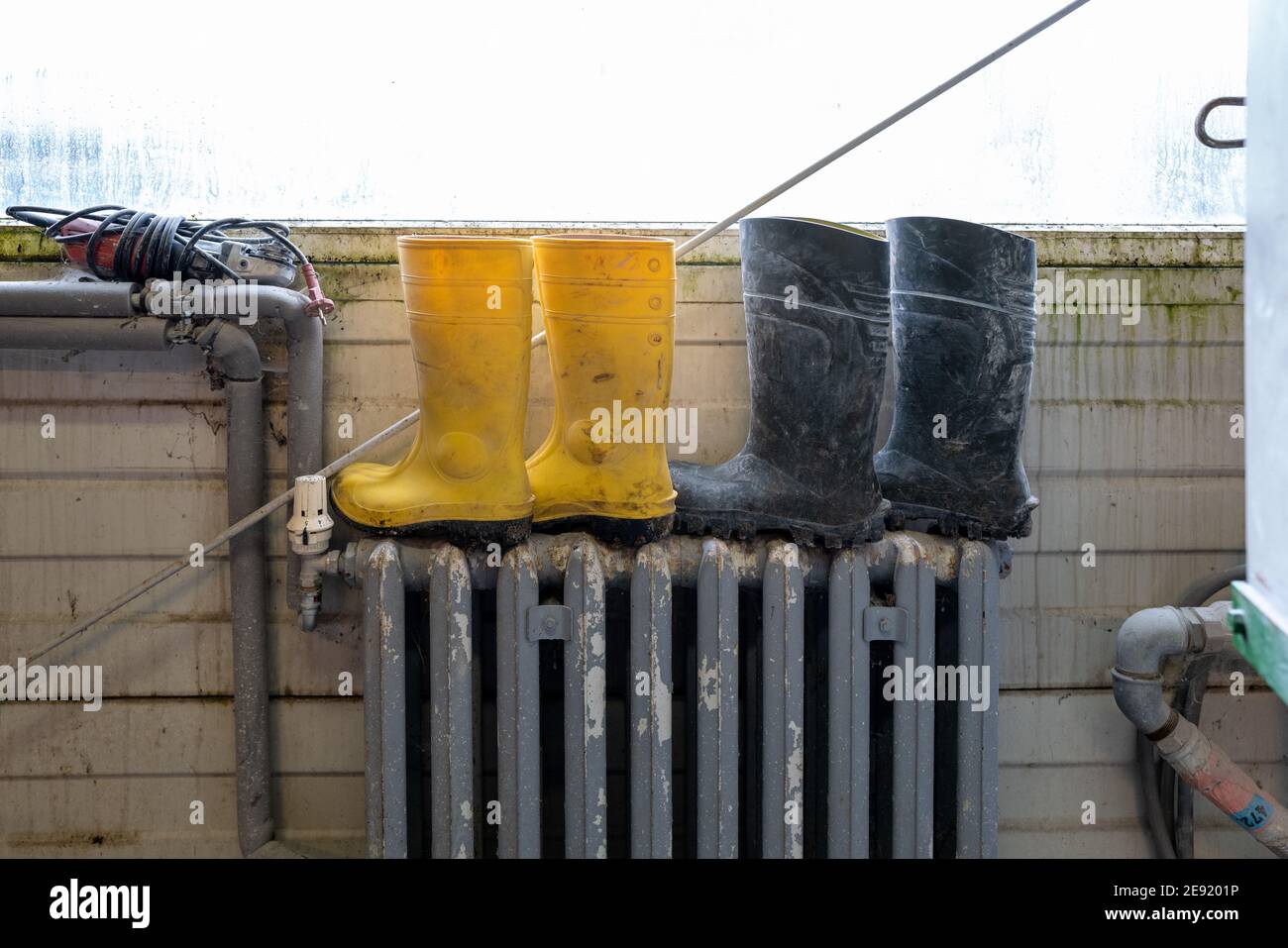two different pairs of rubber boots stand to dry on a radiator Stock ...