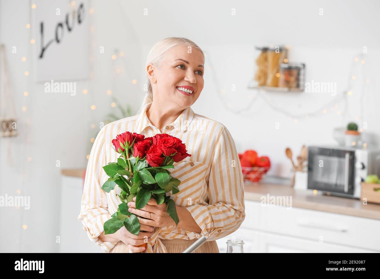 Mature woman with bouquet of beautiful roses at home Stock Photo - Alamy