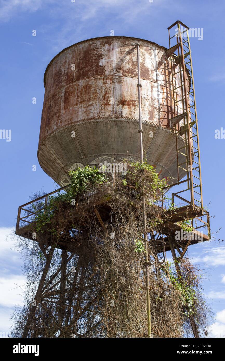 Vertical low angle view of a rustic water tank on a sunny blue day ...