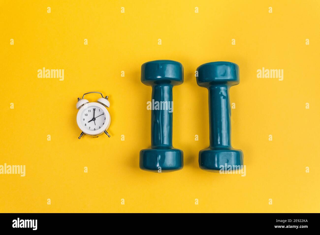 Dumbbell alarm clocks on a yellow background. Morning sports. sport ...