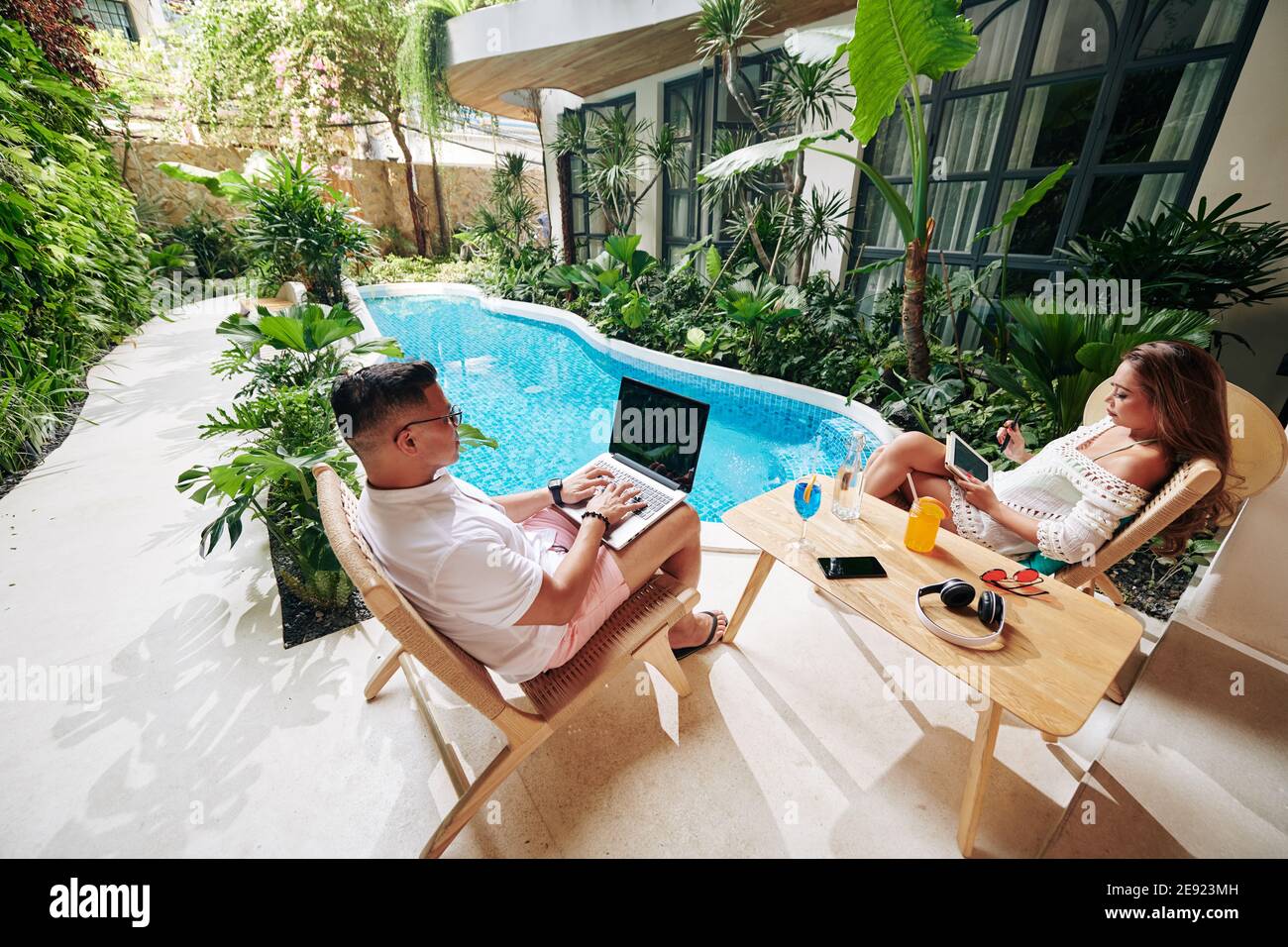 Couple working by swimming pool Stock Photo - Alamy