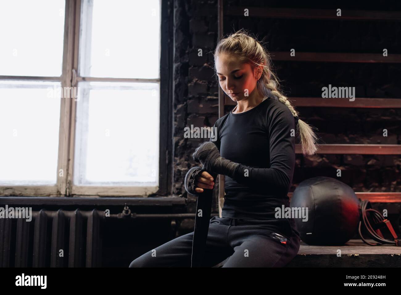 Girl fighter bandages her hands before training in the gym. Red Neon ...