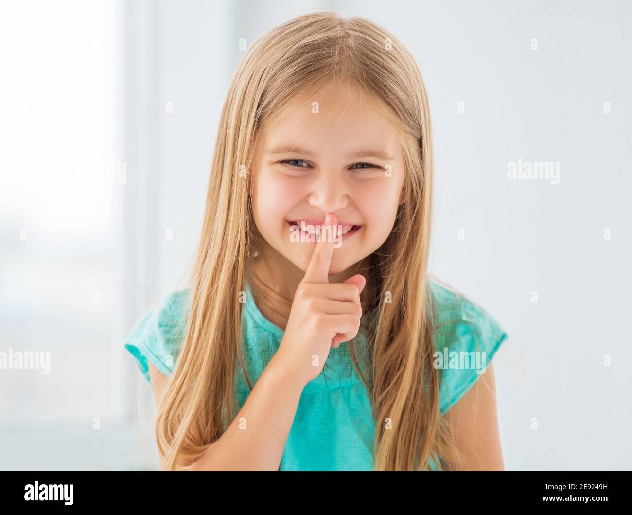 Cute girl laughing showing hush sign Stock Photo - Alamy